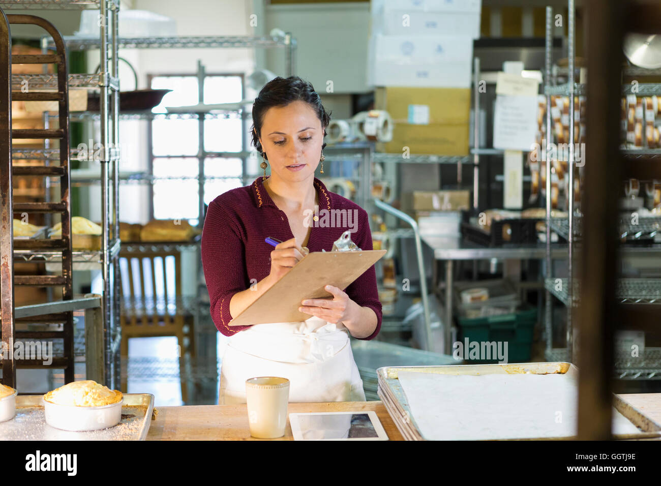 Caucasian woman writing on clipboard in bakery Stock Photo - Alamy