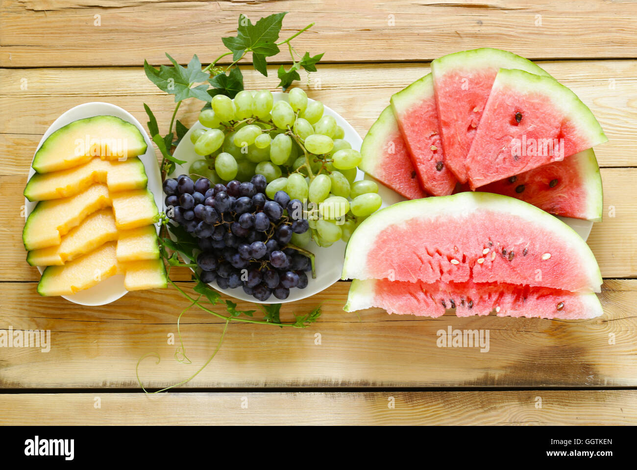 ripe organic fruit watermelon, melon cantaloupe and grapes on a wooden ...