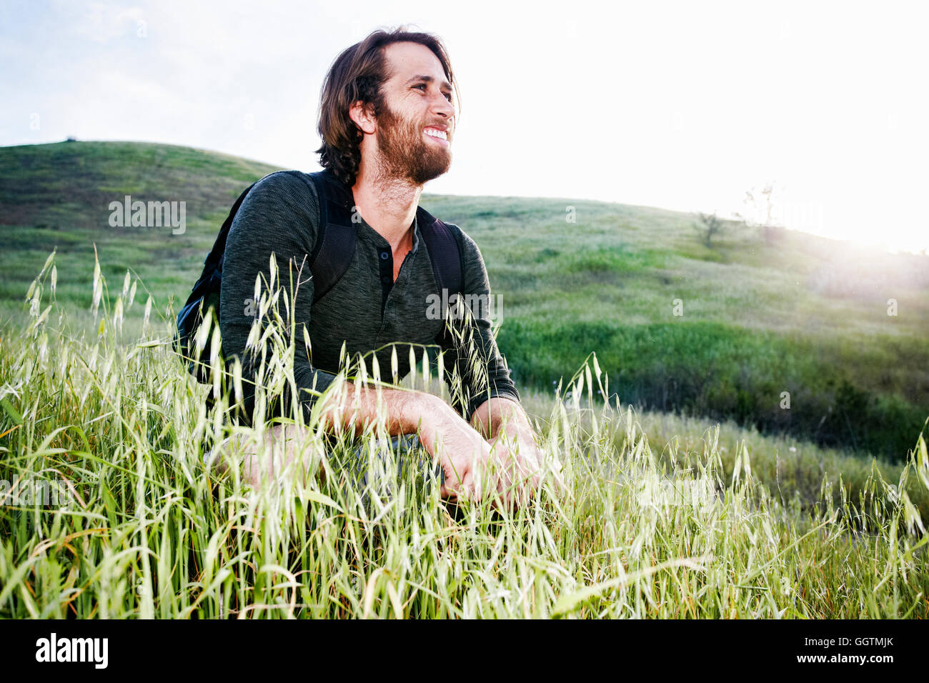 Caucasian hiker crouching in grass on mountain Stock Photo - Alamy