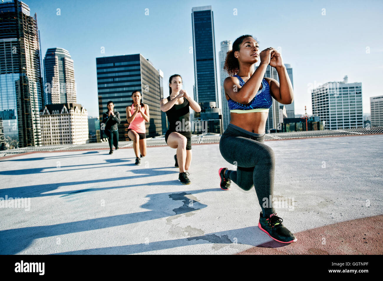 Woman stretching legs on urban rooftop Stock Photo - Alamy