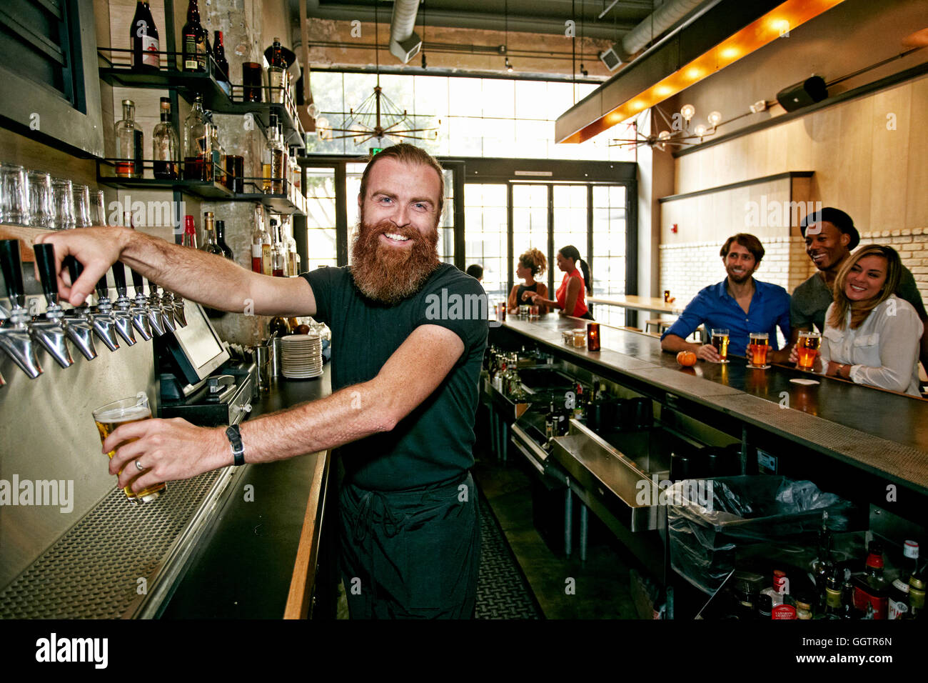 Smiling bartender pouring beer at bar Stock Photo - Alamy