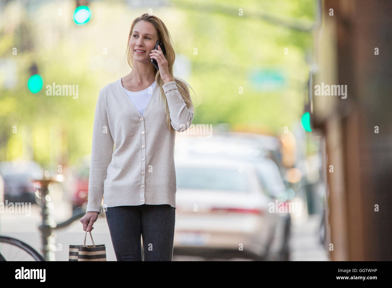 Caucasian woman carrying shopping bag using cell phone Stock Photo - Alamy