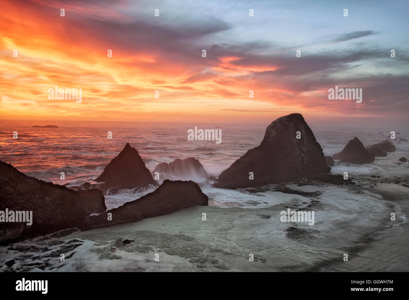 Brilliant sunset silhouettes the many sea stacks and crashing waves at ...
