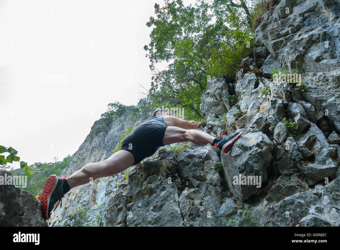 Man free climbing on rocky face of a mountain Stock Photo - Alamy
