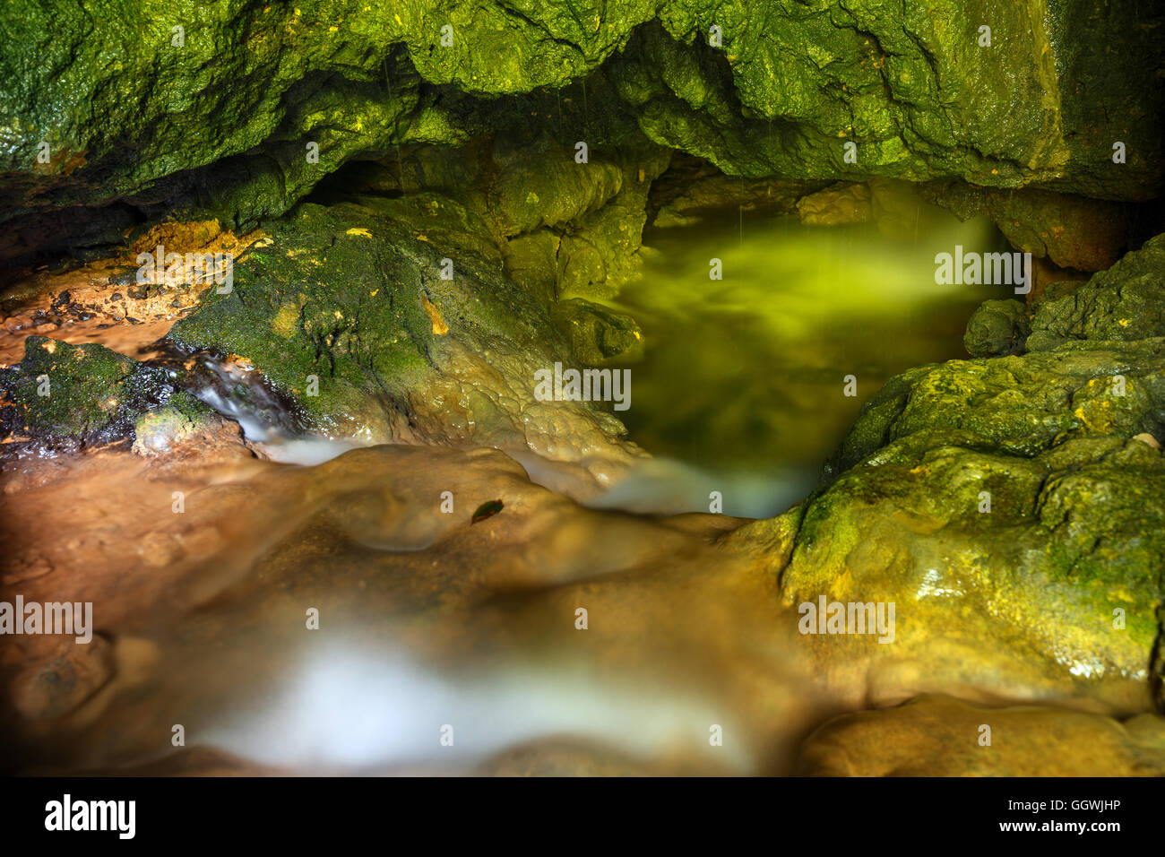Underground river flowing beneath a waterfall in limestone mountains ...