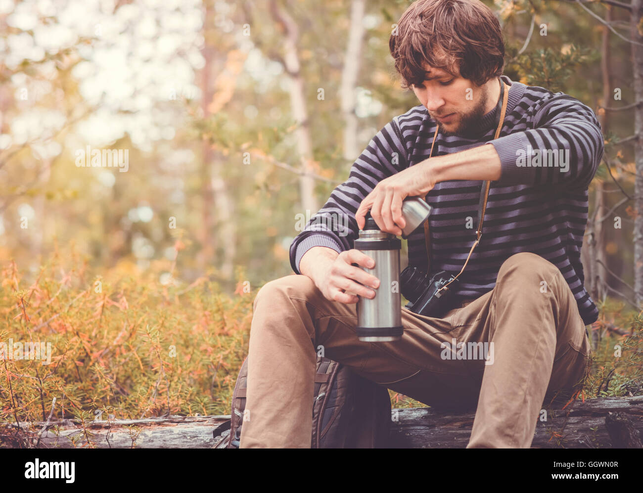 Traveler Man relaxing in forest with thermos, backpack and photo camera ...