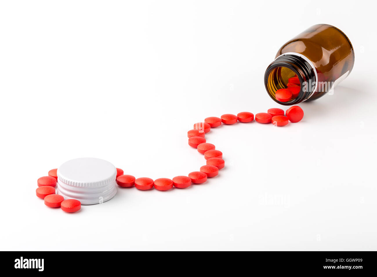 Spilled from a glass apothecary bottle red pills on white background ...