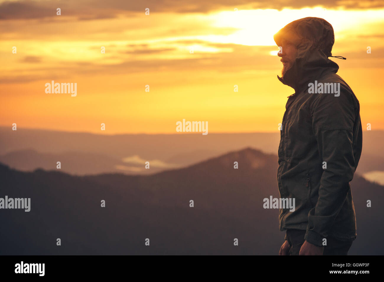 Young Man standing alone outdoor with sunset mountains on background ...