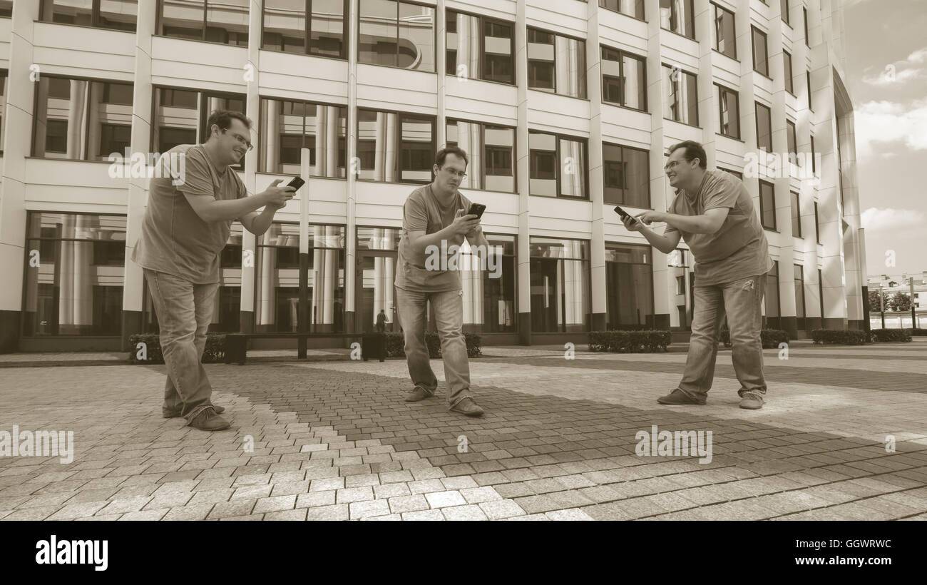 Three men with a mobile phone in front of a white business center ...