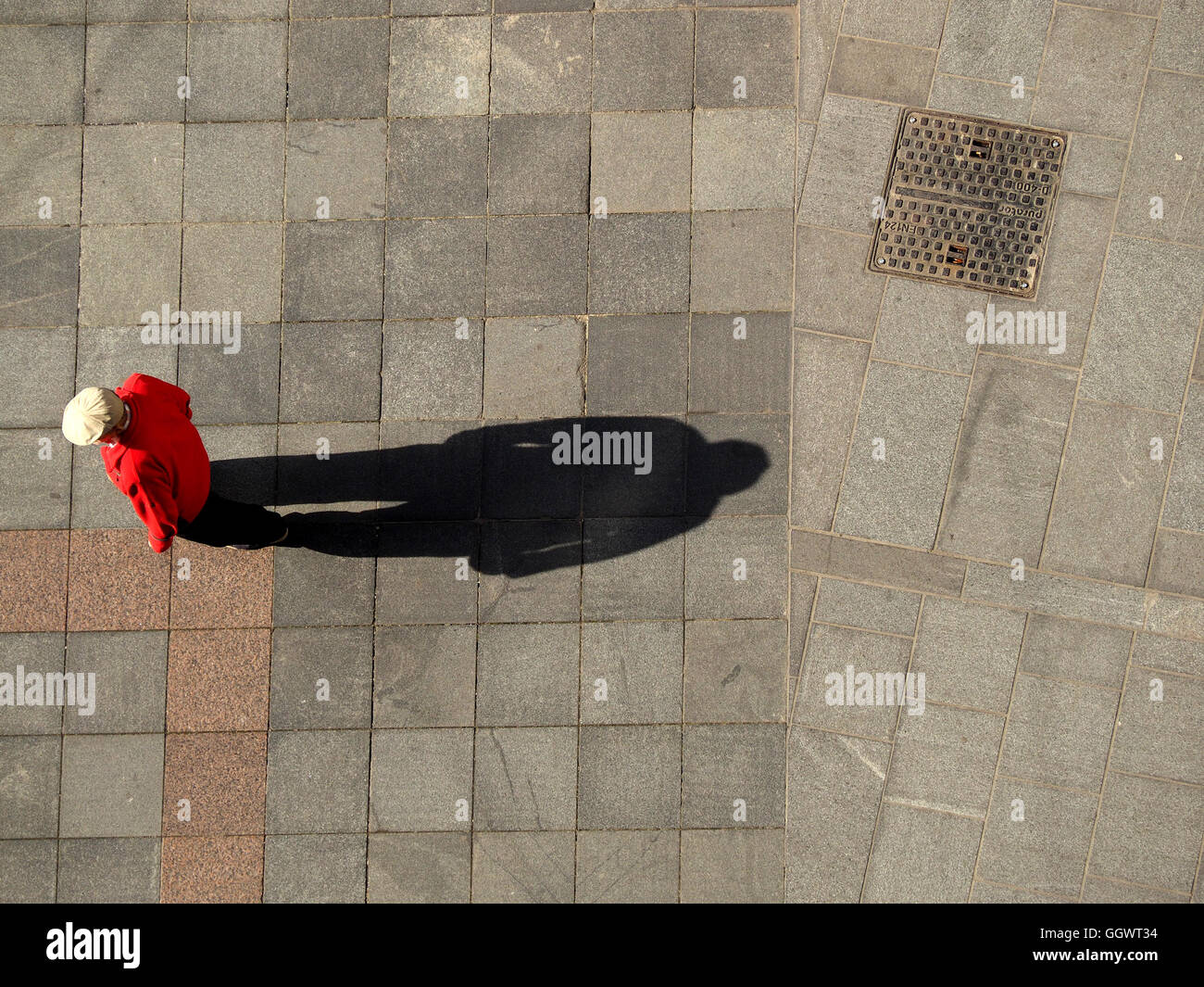 Overhead view of single tourist with red coat and white cap walking in ...