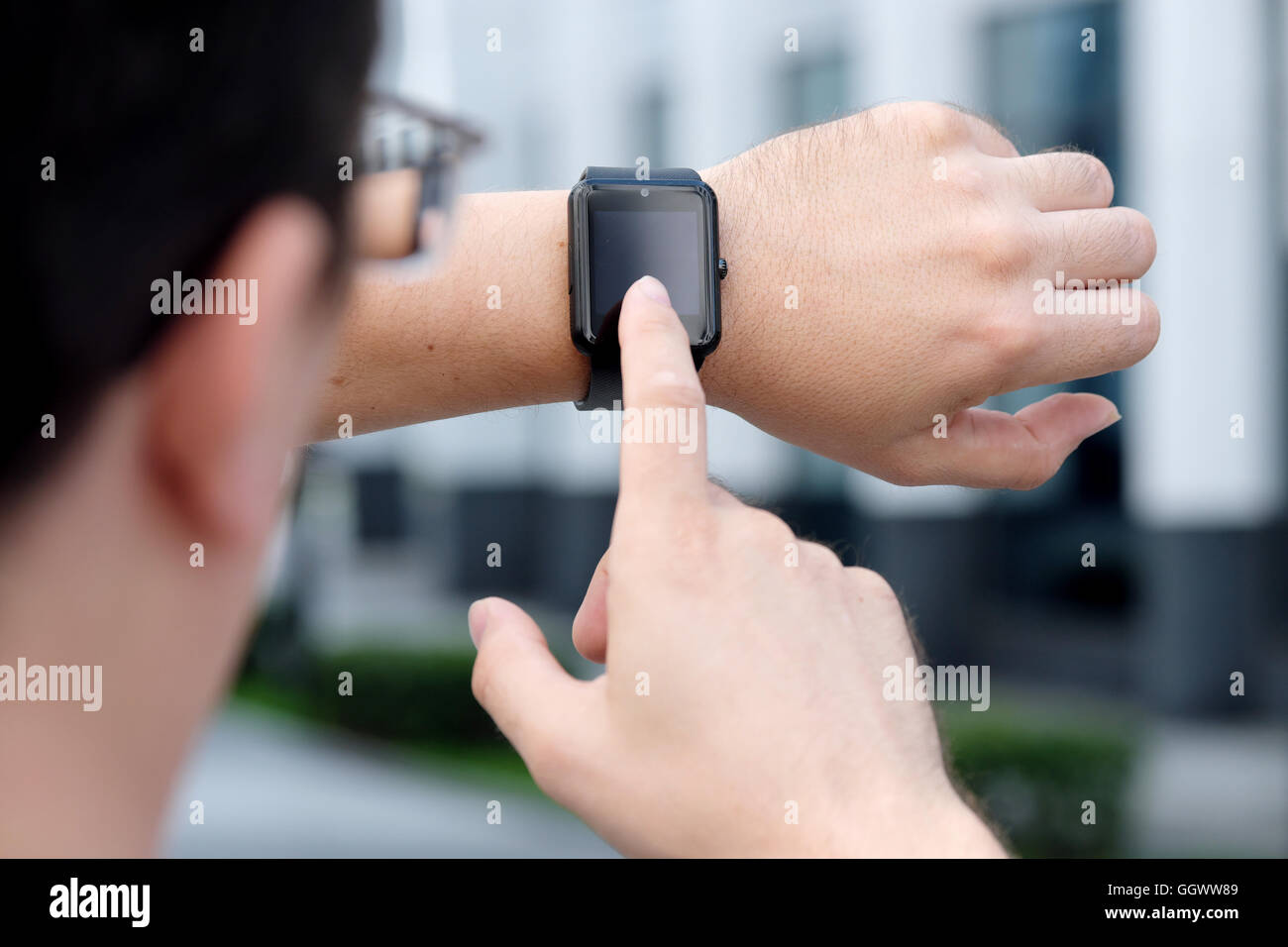 Adult stylish and fashionable man checking his smartwatch outdoors ...