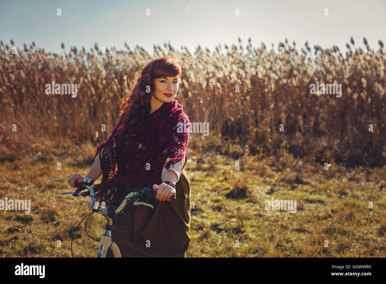 Pretty girl riding bicycle in field Stock Photo - Alamy