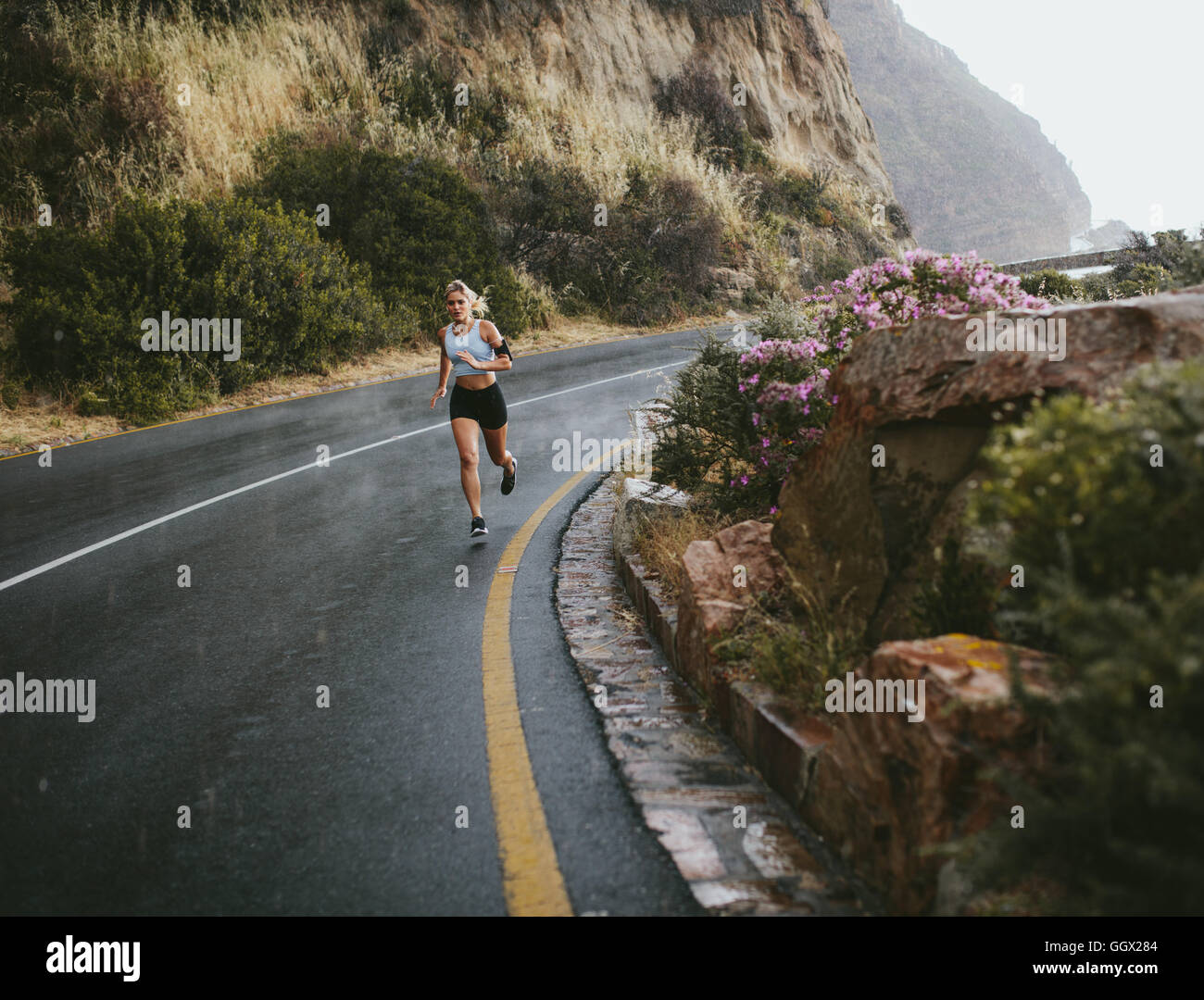 Full length shot of fitness woman running outdoors on highway in ...