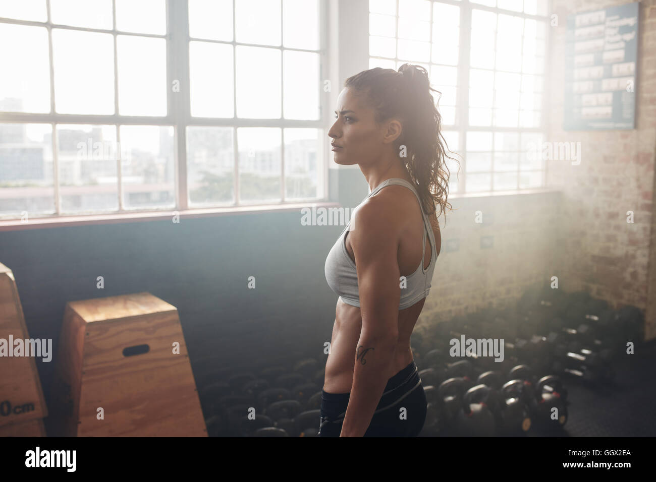 Side portrait of healthy crossfit woman relaxing in the gym with ...