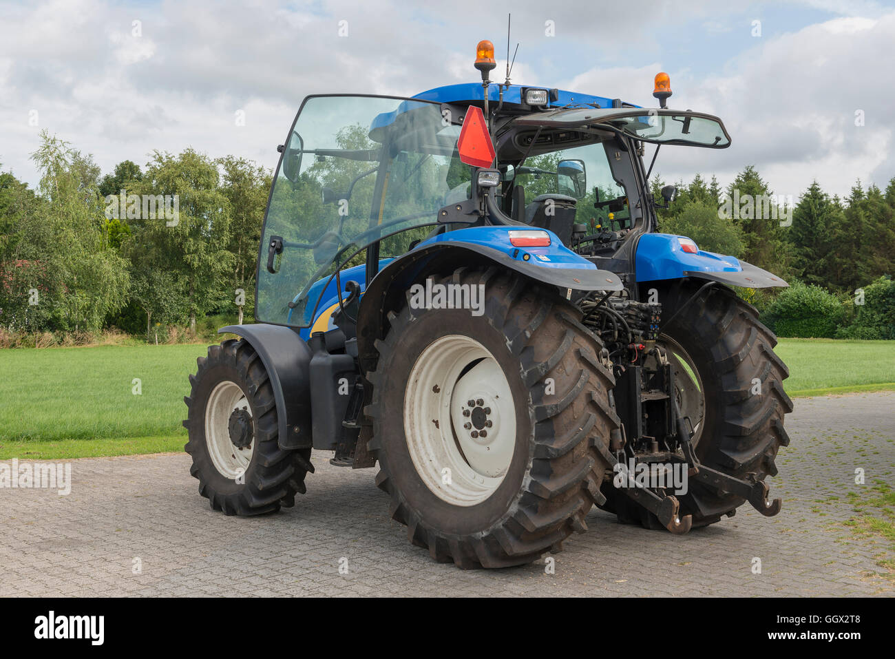 Modern blue tractor on a paved farmyard Stock Photo - Alamy
