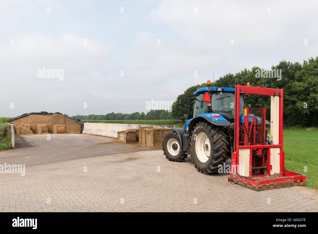 Blue tractor with a red bale slicer for cutting off silage bales Stock ...