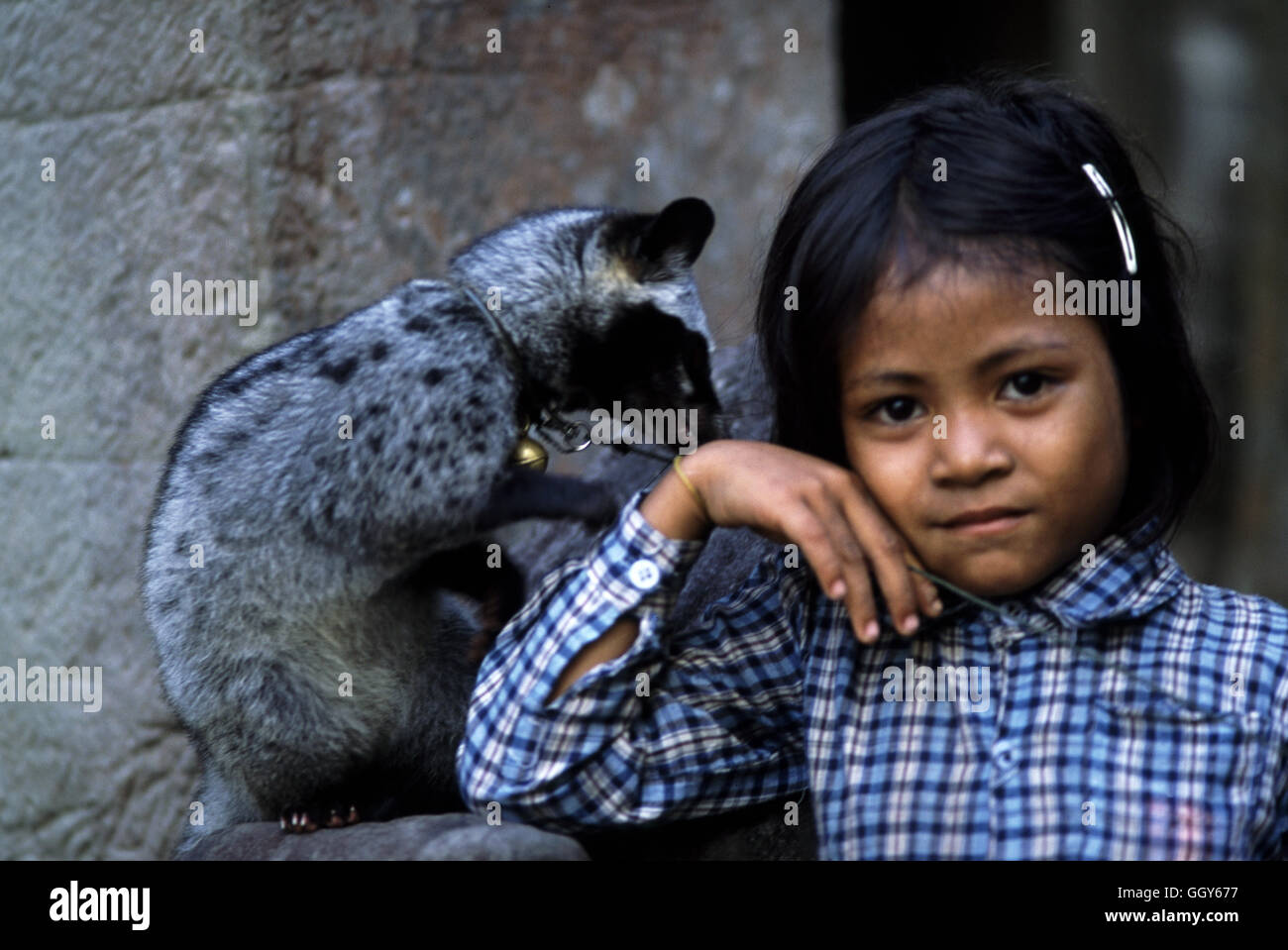 Young girl and her pet civet cat (genus Viverar) in the ruins of the Ta ...