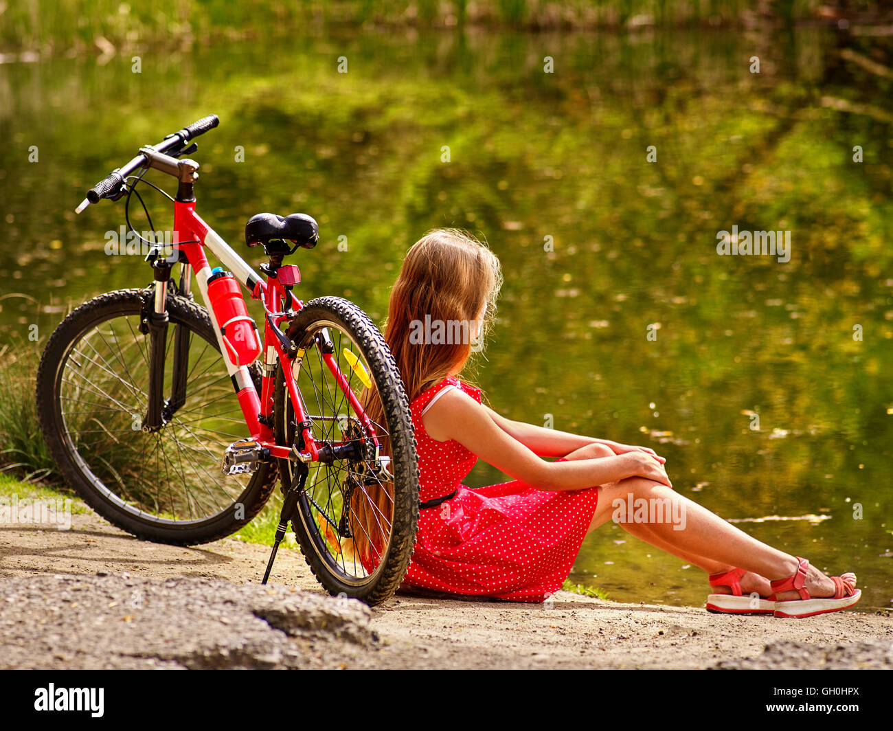 Bikes cycling girl into park sits leaning bicycle on shore Stock Photo ...