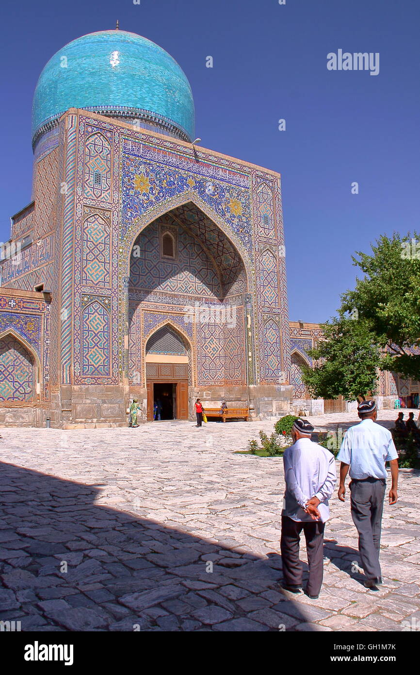 Two Uzbek men with an Uzbek hat walking in the courtyard of a madrasa ...