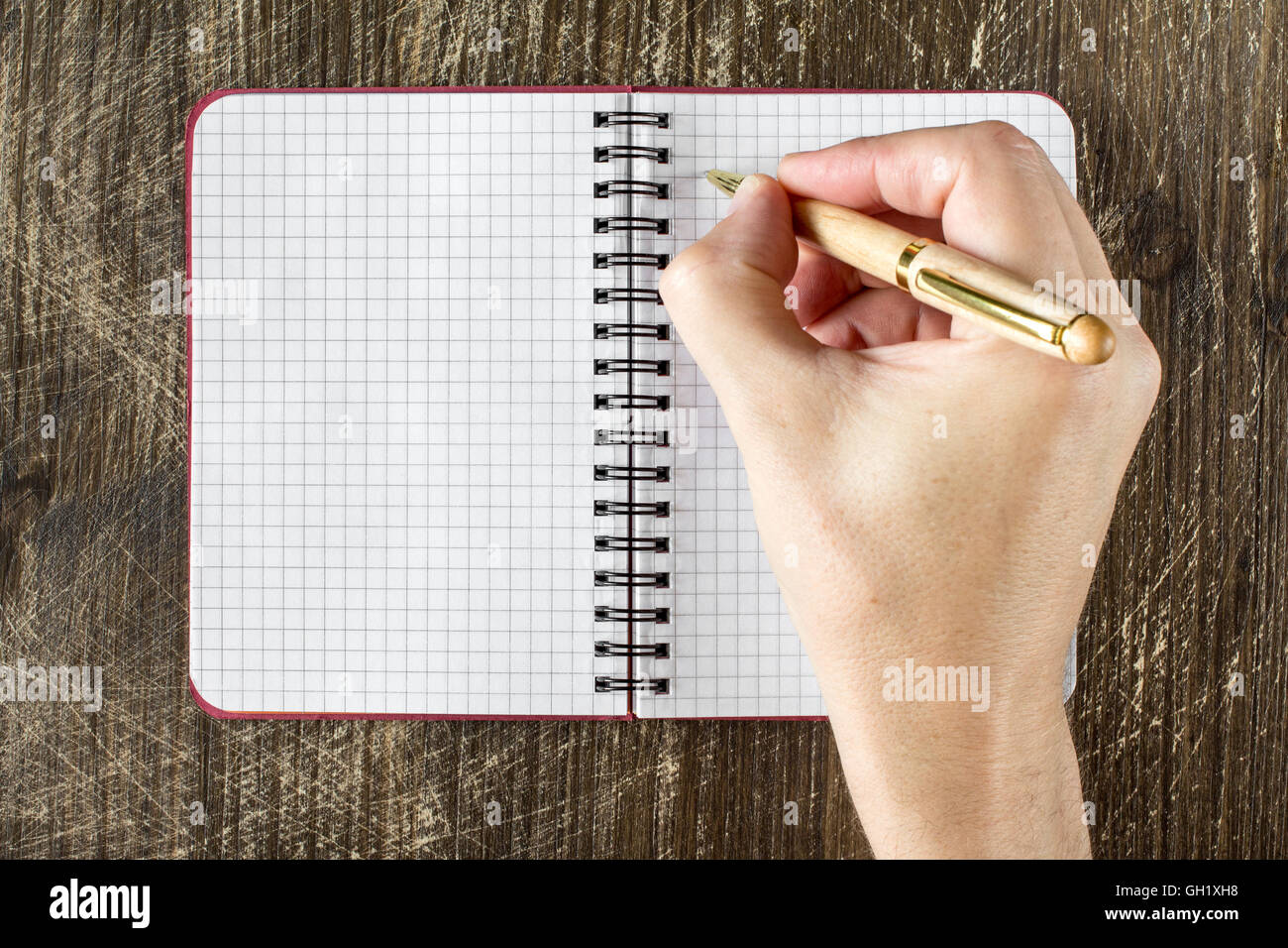 Hand is writing in a notepad on a wooden table Stock Photo - Alamy