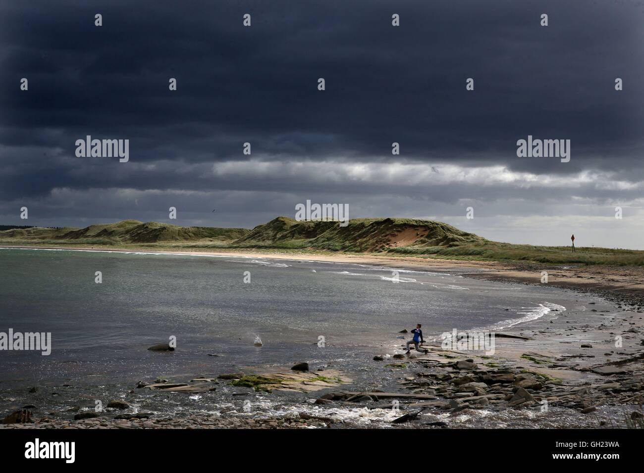 A boy skims stones on the beach at Dunnet Bay in the Highlands of ...