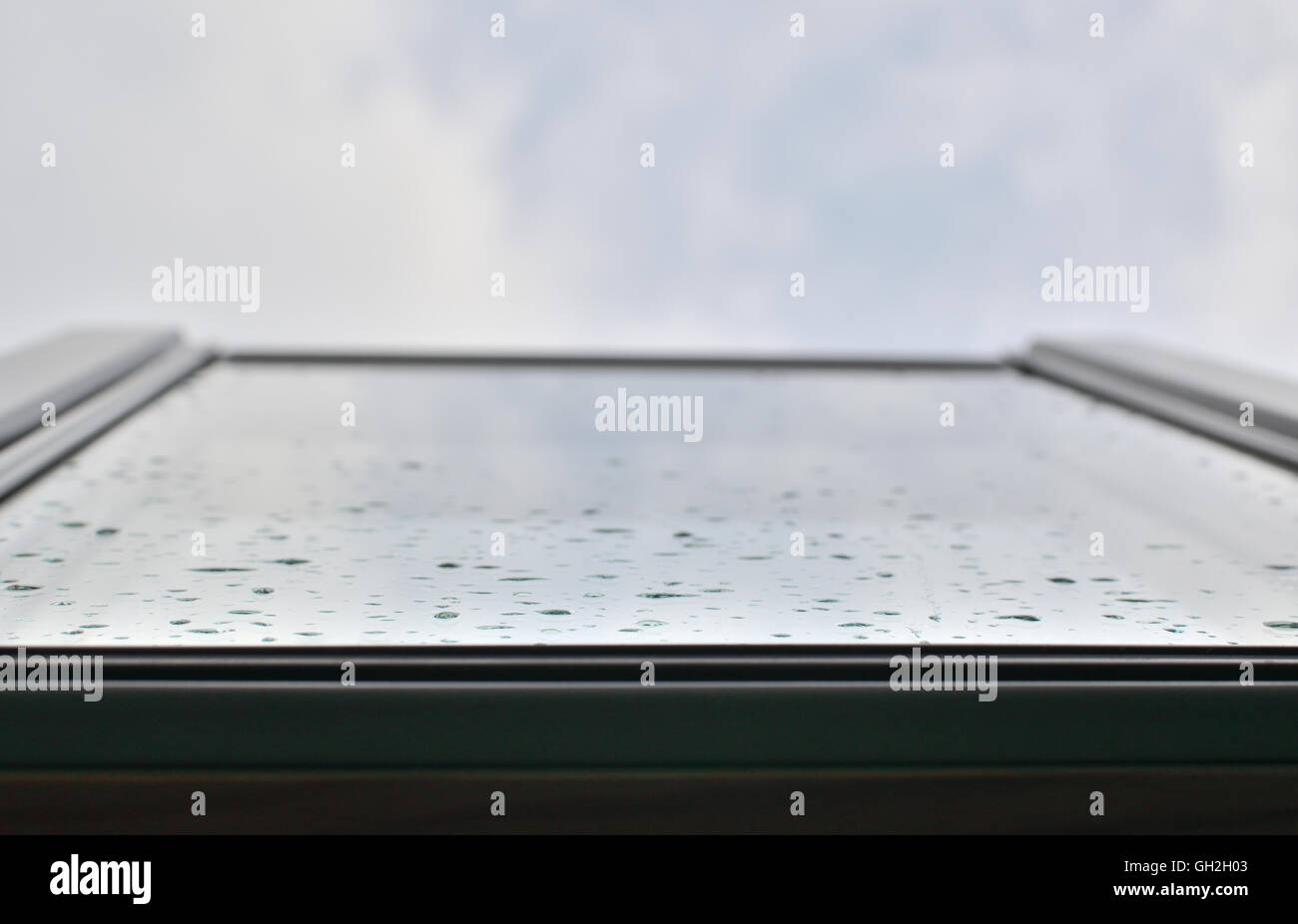 Opened roof window with raindrops, with a view to the overcast sky, on ...