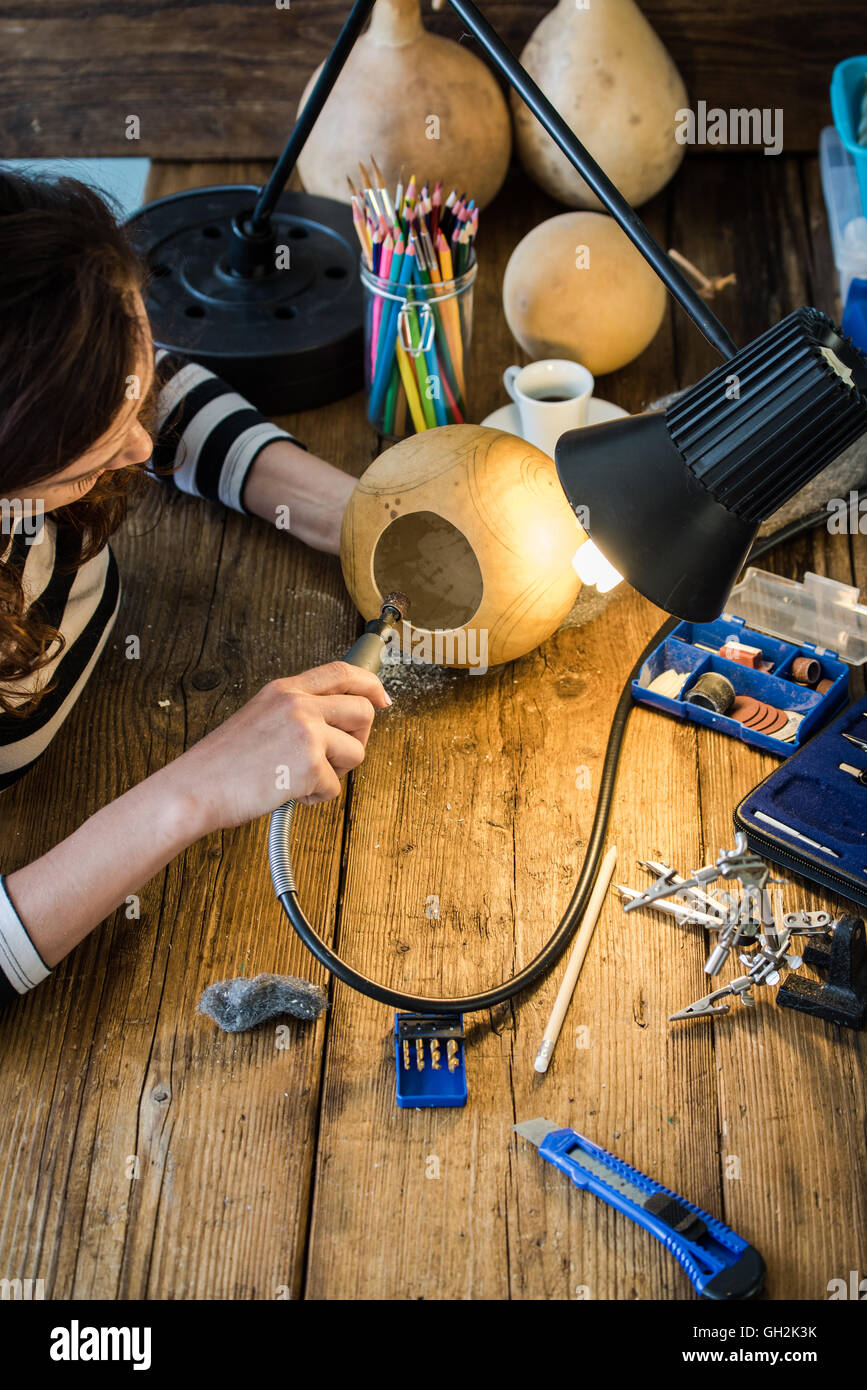 young woman using tools for creative craft, working with calabash and ...