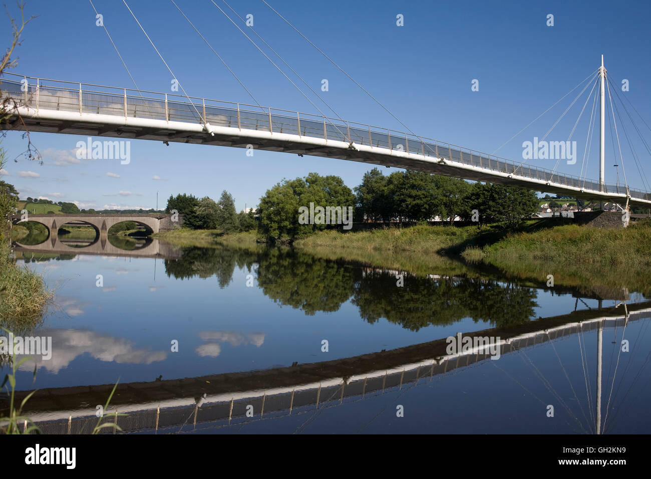 Pedestrian bridge and more distant road bridge reflected in River Towy ...