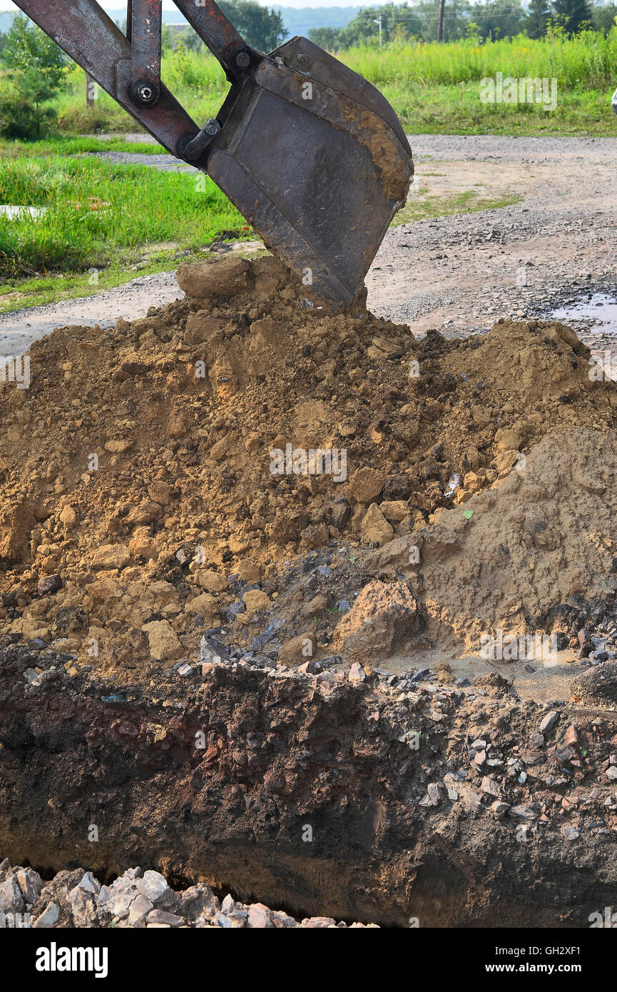 Excavator bucket digging a trench in the dirt ground Stock Photo - Alamy