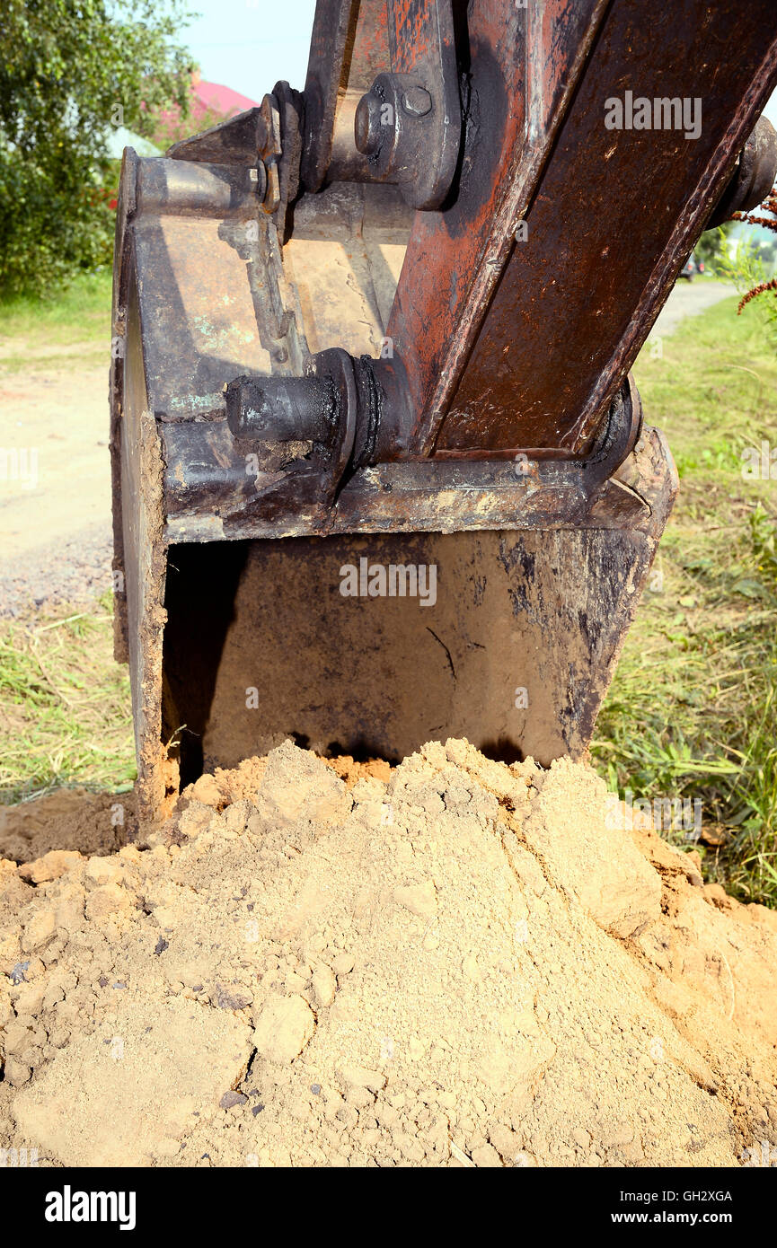 Excavator bucket digging a trench in the dirt ground Stock Photo - Alamy