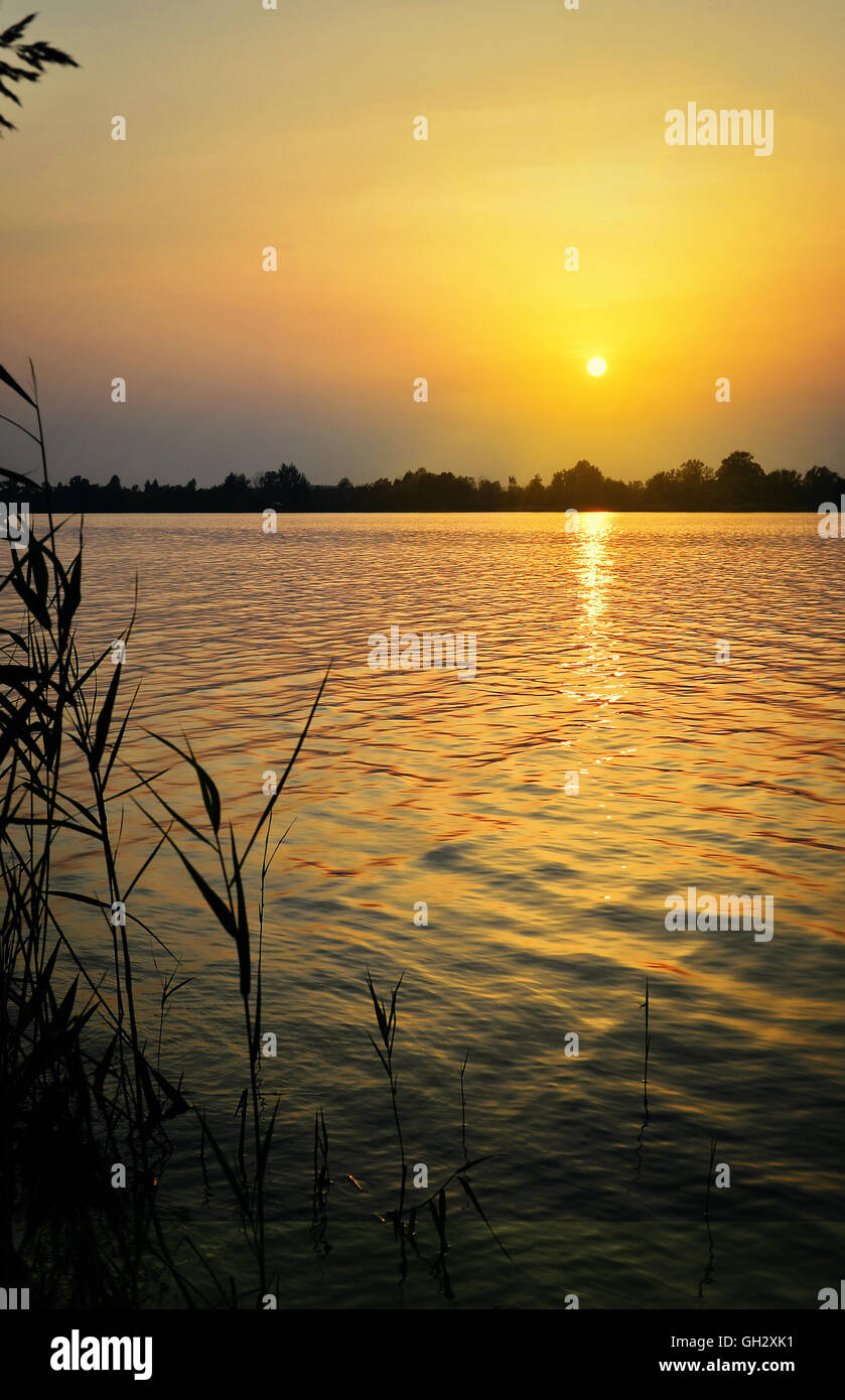 Landscape with sunset over the lake with the reflection of light on the ...