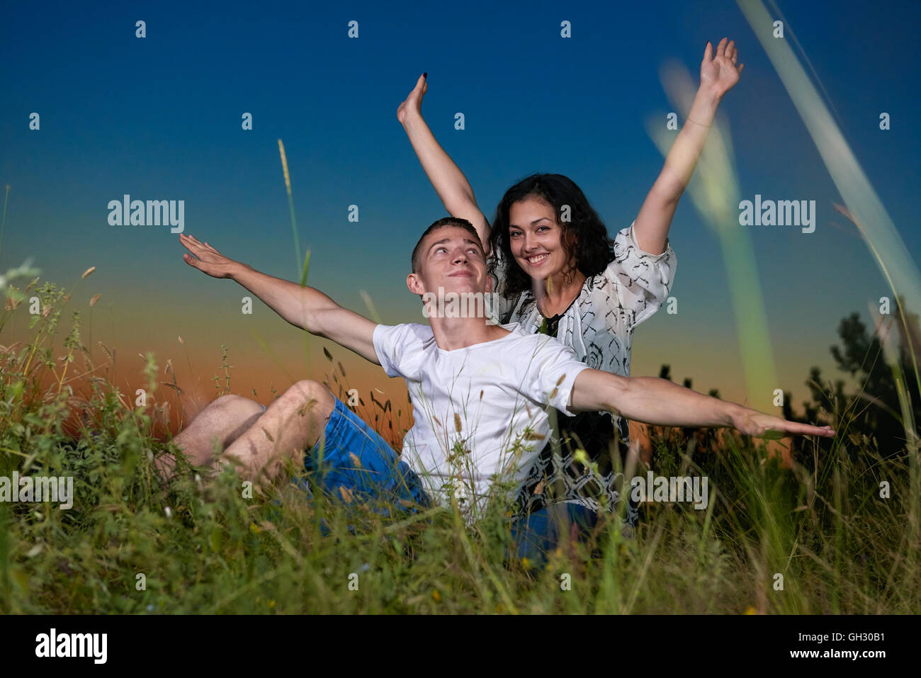 young romantic couple open arms and having fun at sunset on outdoor ...