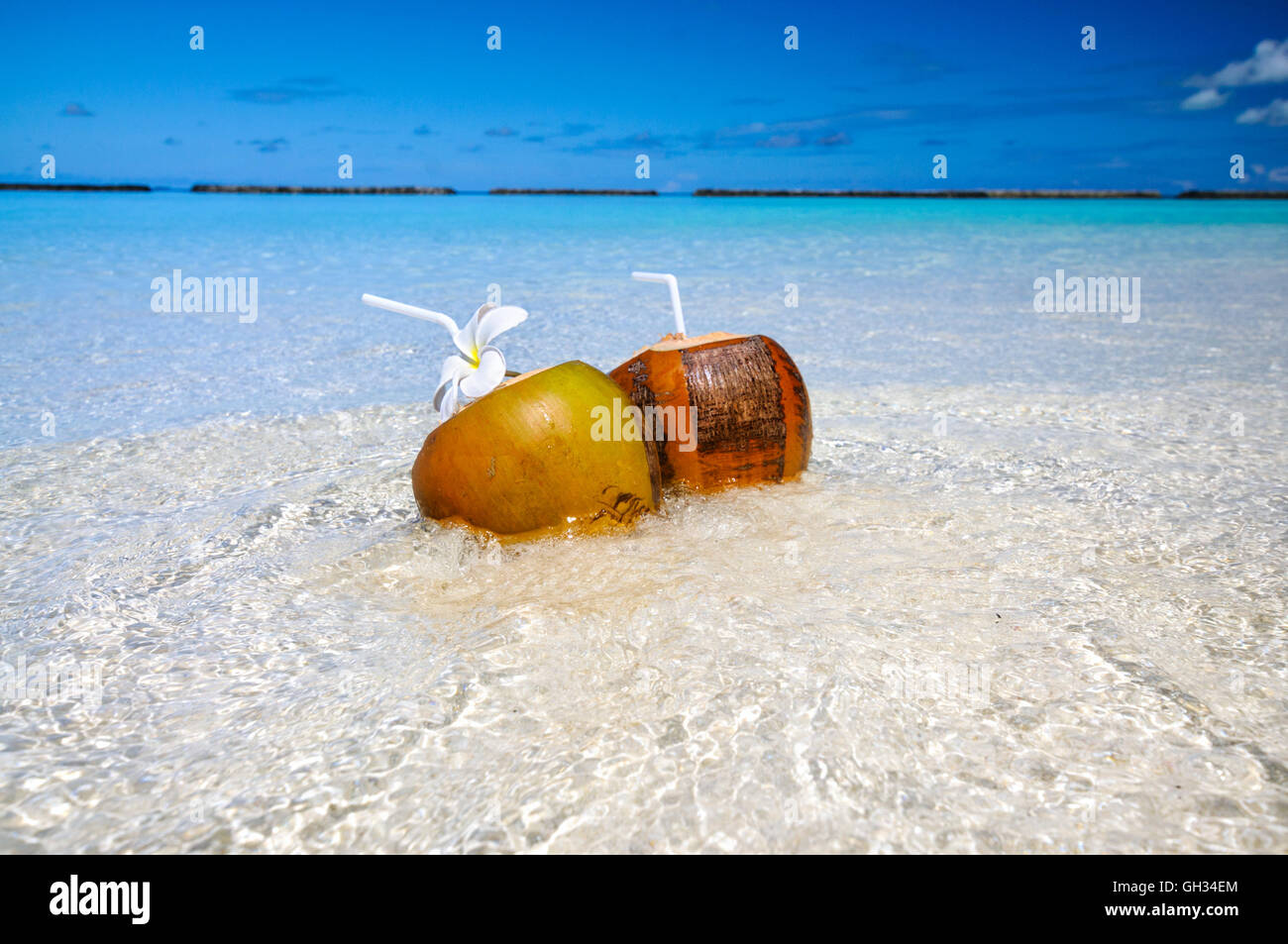 Two coconut cocktails on white sand beach next to clean sea water ...