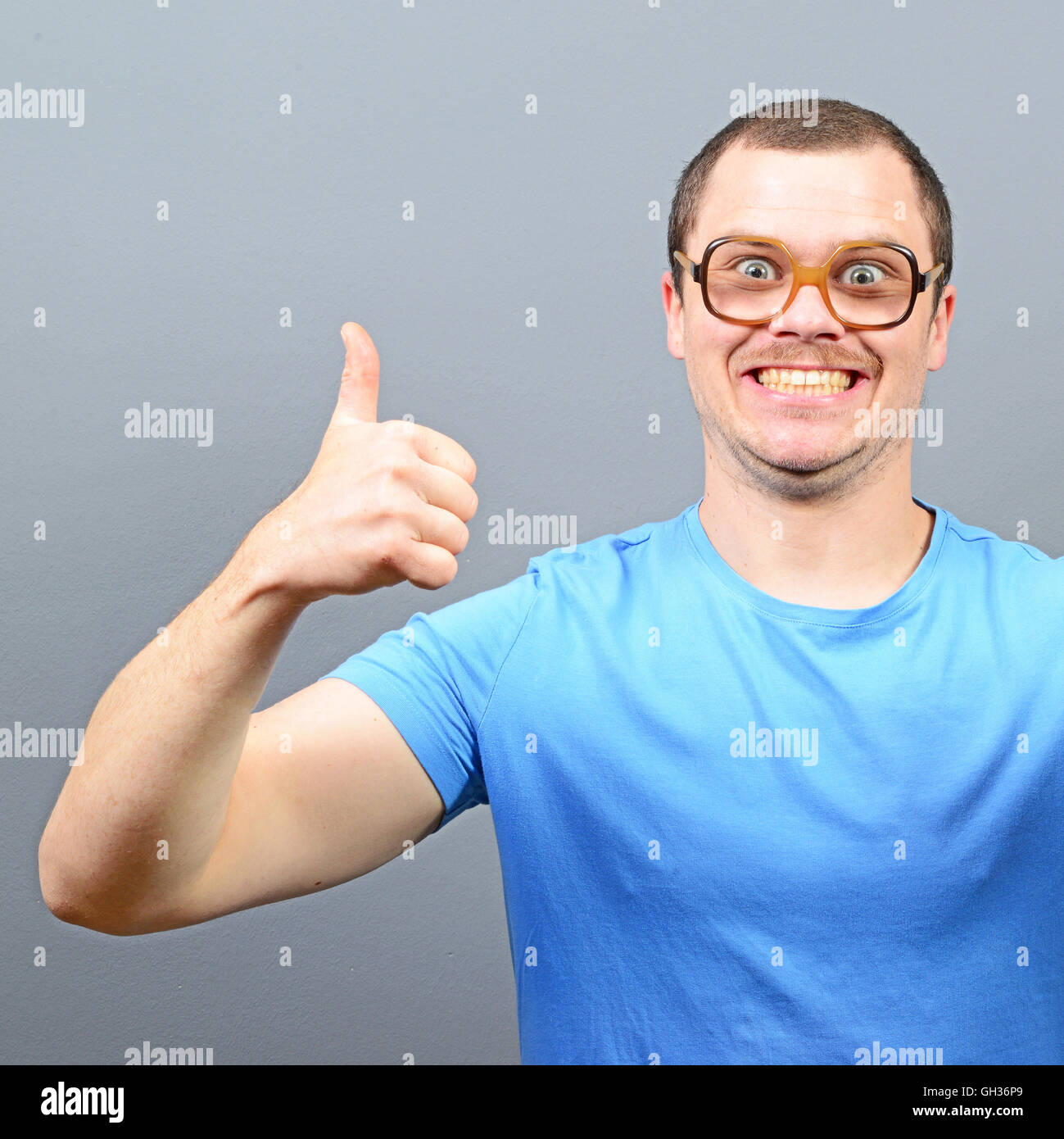 Portrait of a geek showing thumbs up against gray background Stock ...