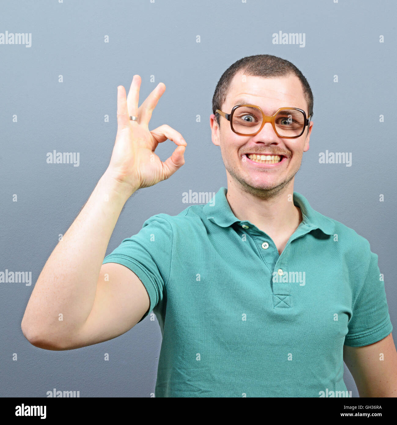 Portrait of a man showing ok sign against gray background Stock Photo ...