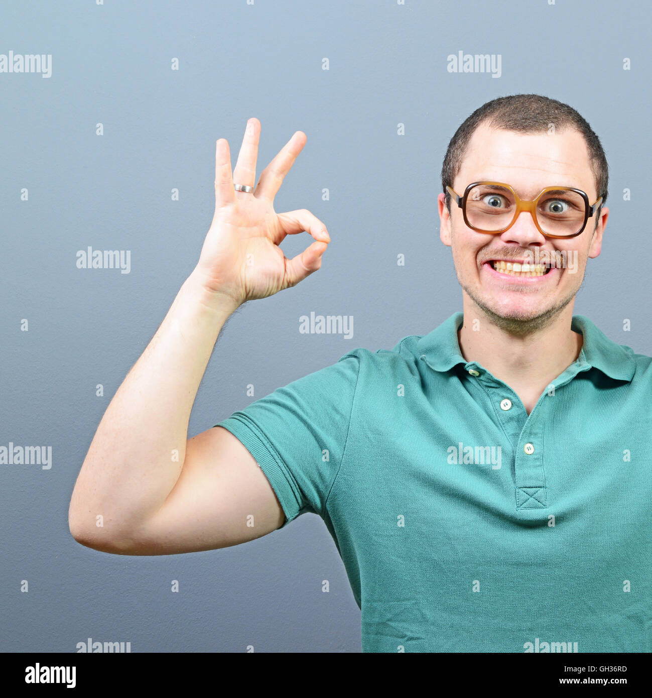 Portrait of a man showing ok sign against gray background Stock Photo ...