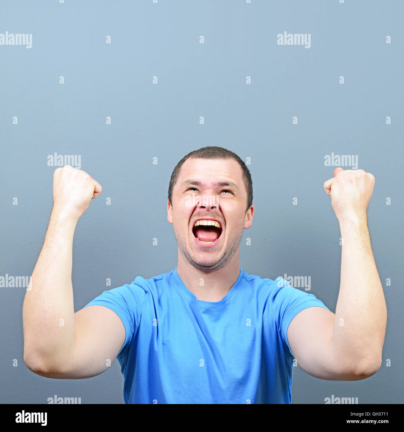 Portrait of ecstatic young man celebrating victory or win against gray ...