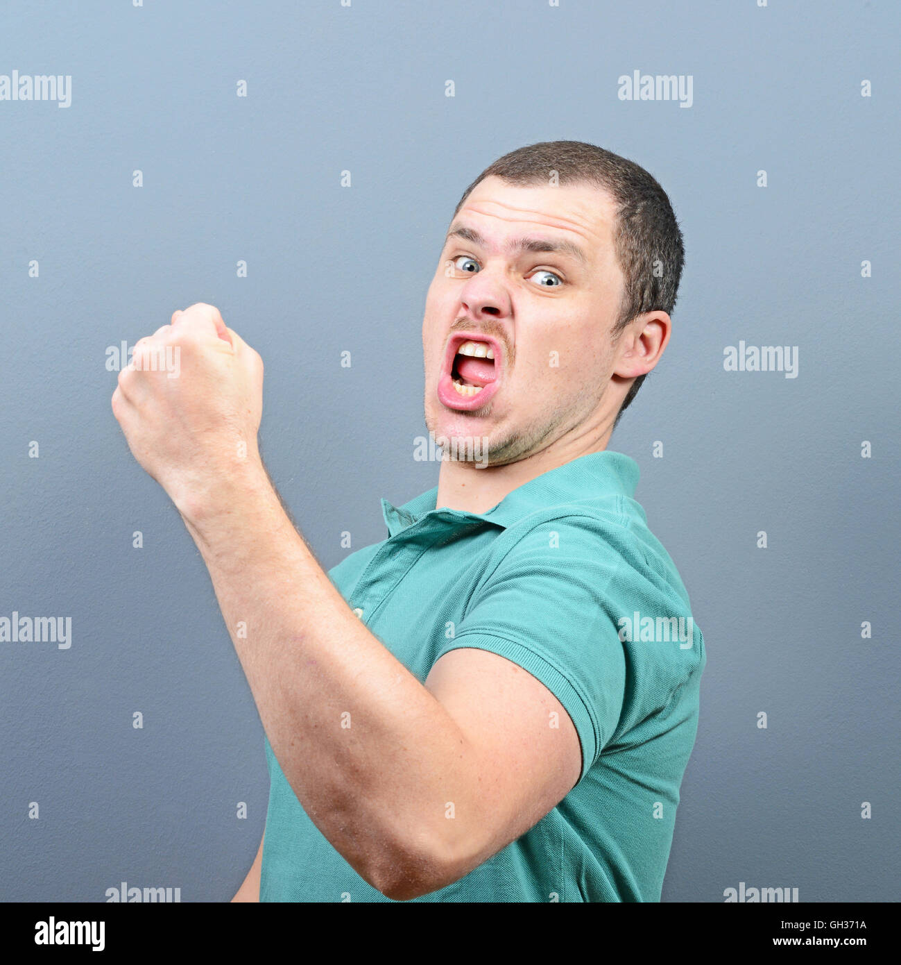 Portrait of ecstatic young man celebrating victory or win against gray ...