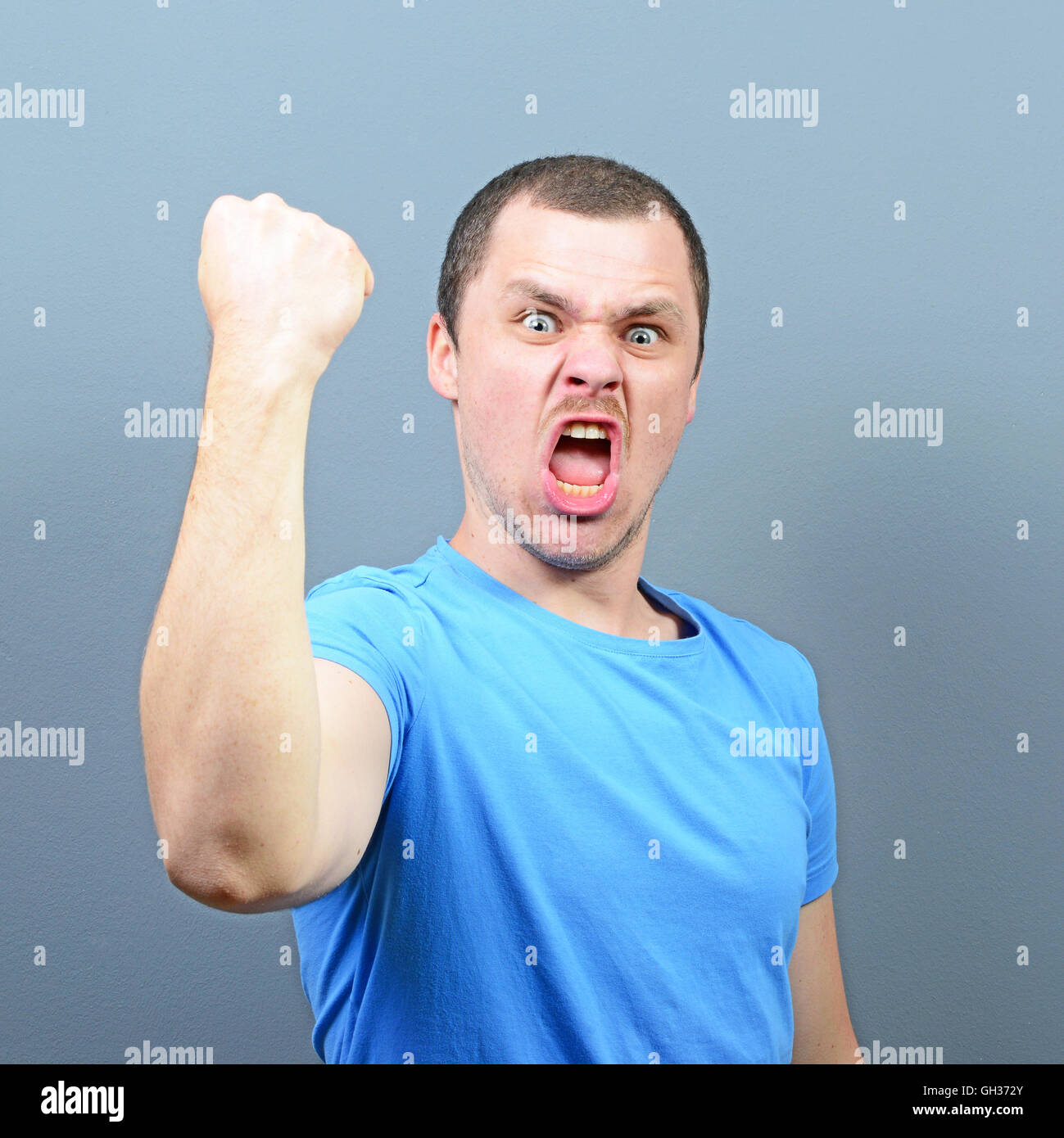 Portrait of ecstatic young man celebrating victory or win against gray ...