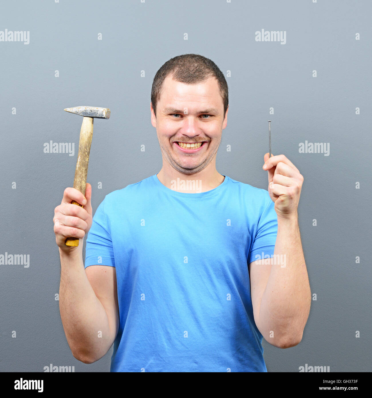 Portrait of funny man holding hammer and nail Stock Photo - Alamy