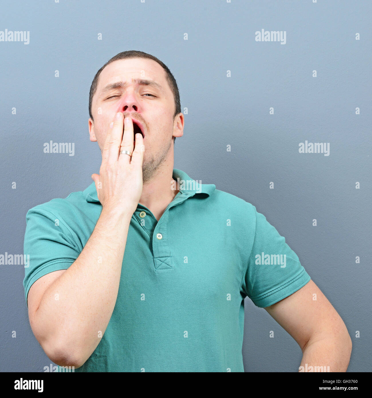 Portrait of man yawning against gray background Stock Photo - Alamy