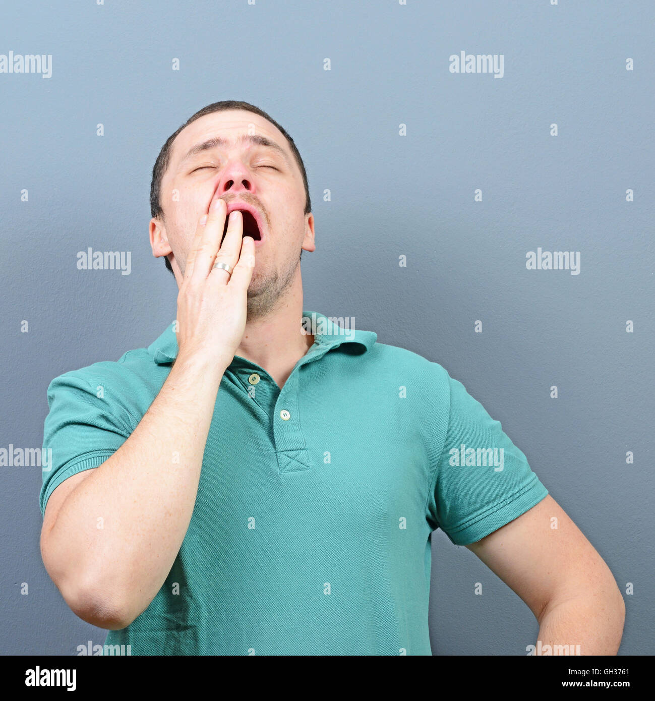 Portrait of man yawning against gray background Stock Photo - Alamy