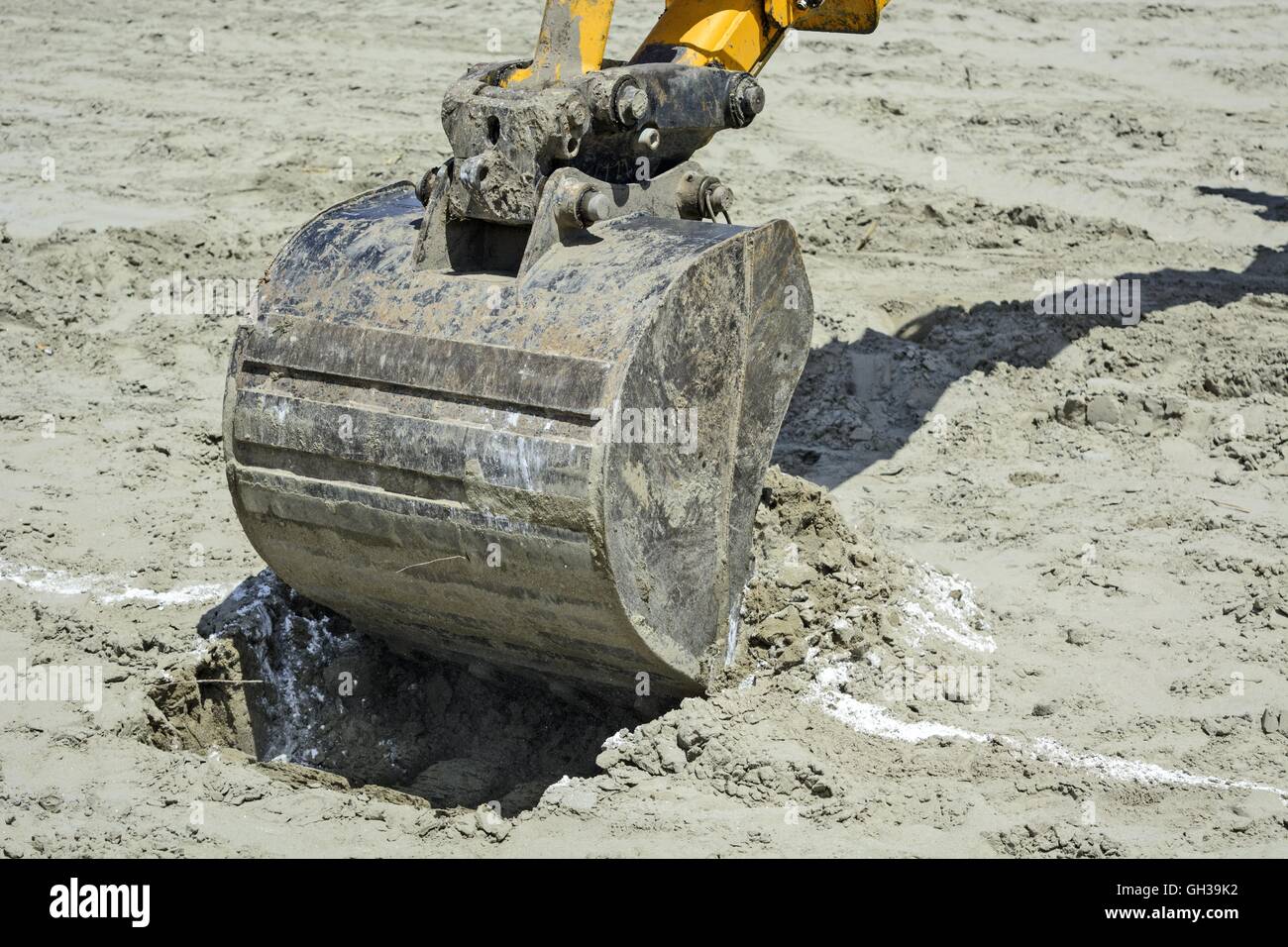 Excavator in a situation digs holes in the sandy ground Stock Photo - Alamy