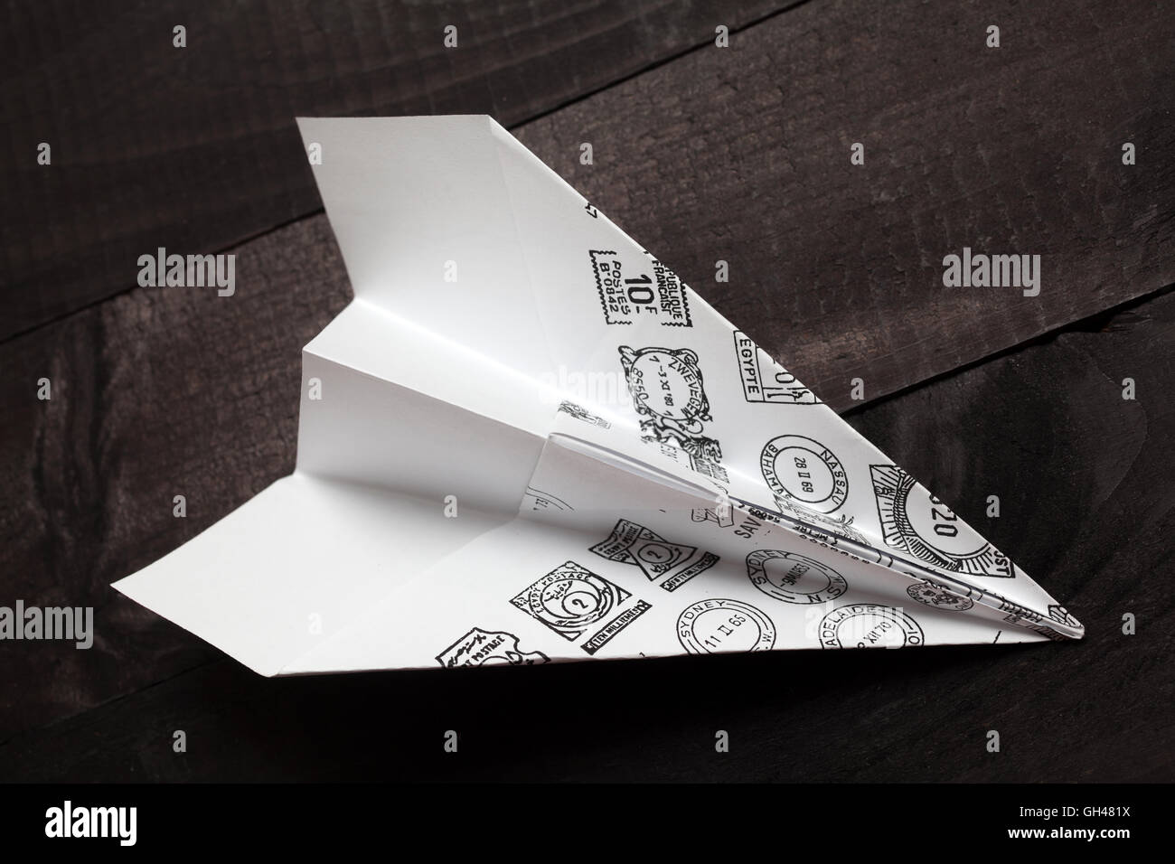 Paper airplane with mail stamps on black background Stock Photo - Alamy