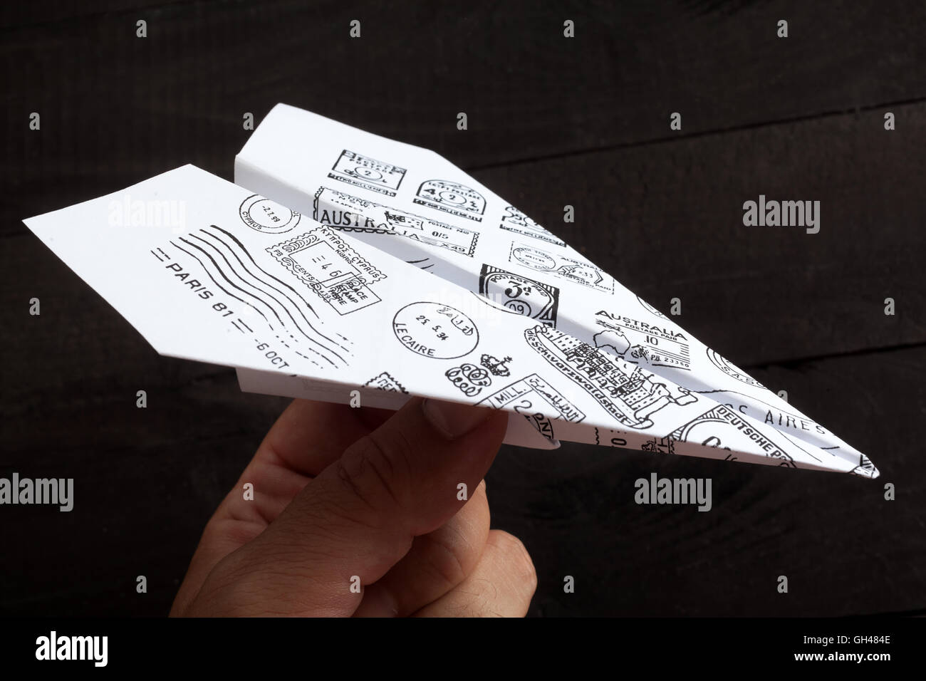 Paper airplane with mail stamps on black background Stock Photo - Alamy