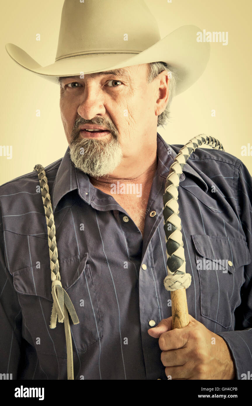 Cowboy holding a bullwhip around his shoulder. Retro instagram look ...