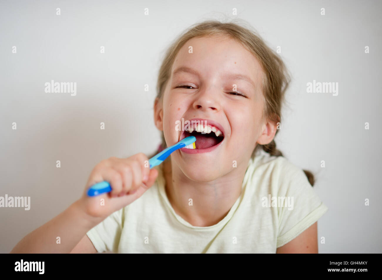 Cute little girl with pigtails diligently brushing his teeth. In the ...