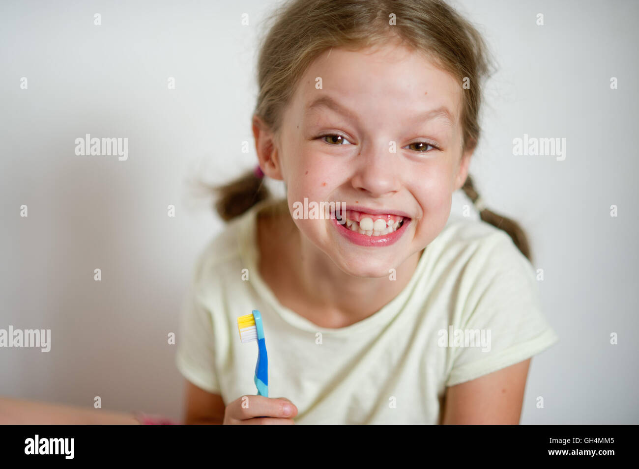 Funny girl with pigtails brushing his teeth. She shows their clean ...
