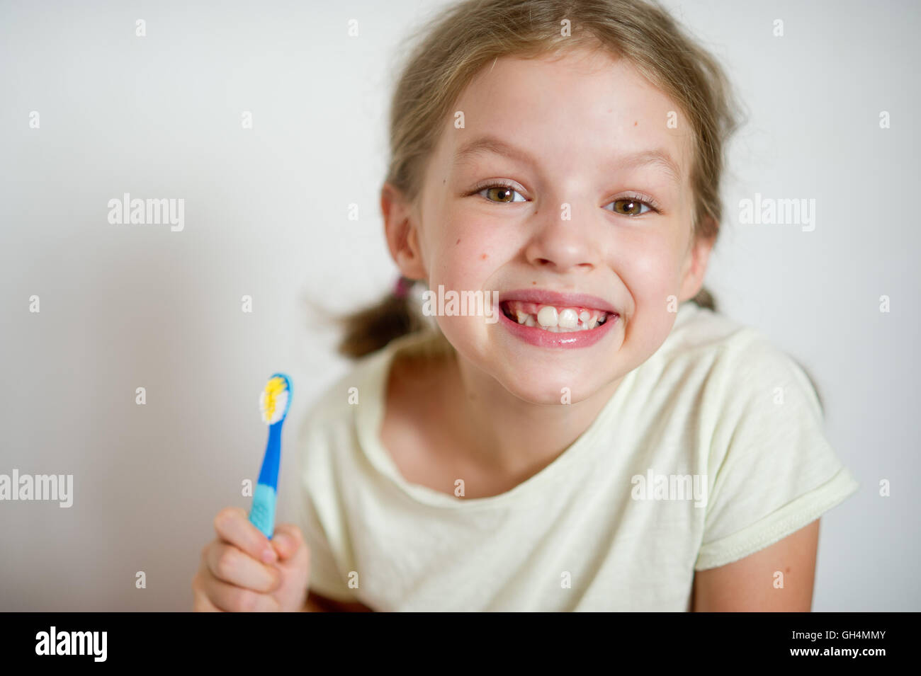 Funny girl with pigtails brushing his teeth. She shows their clean ...