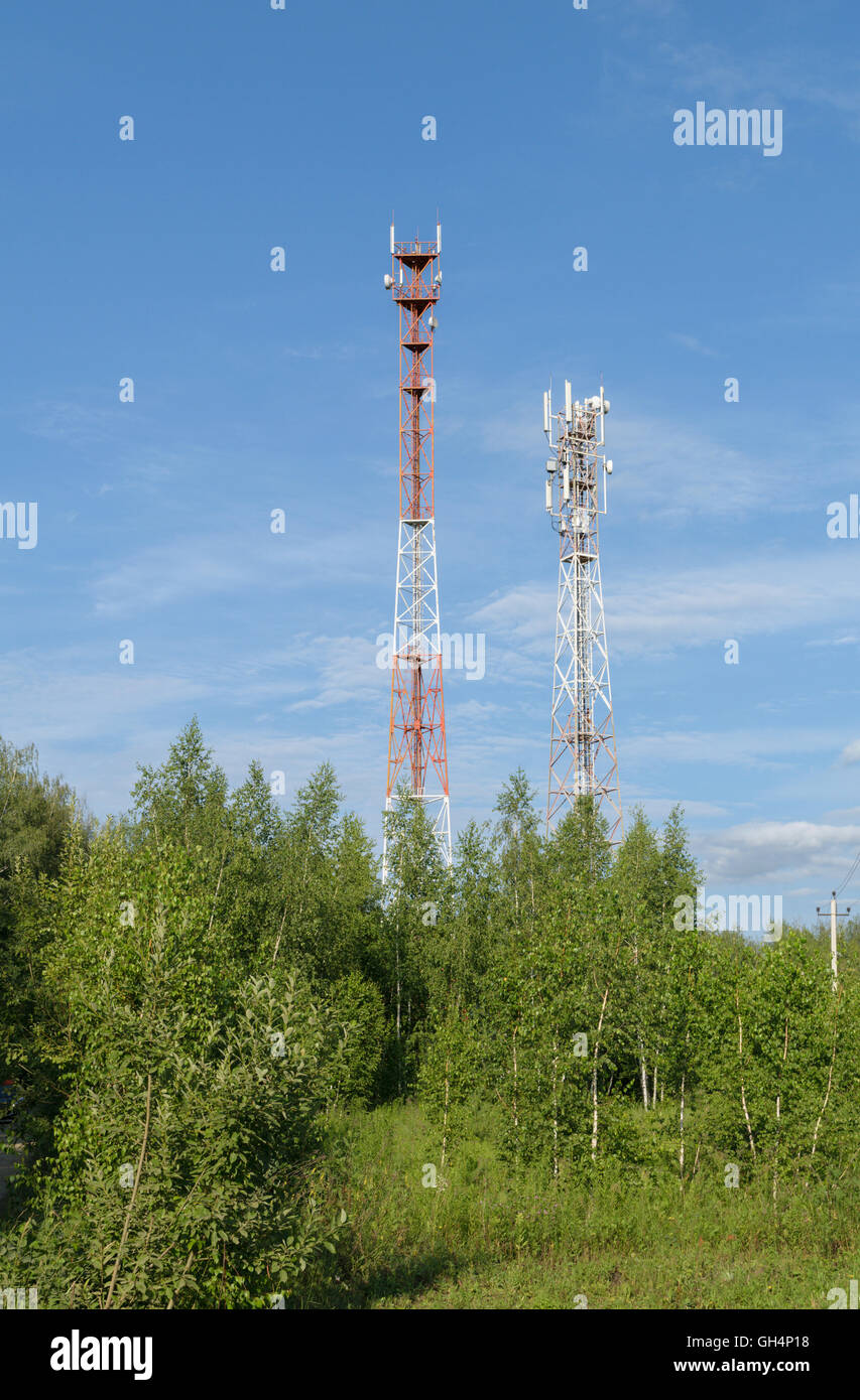 Two towers with a cellular mobile radio antennas are among the trees ...